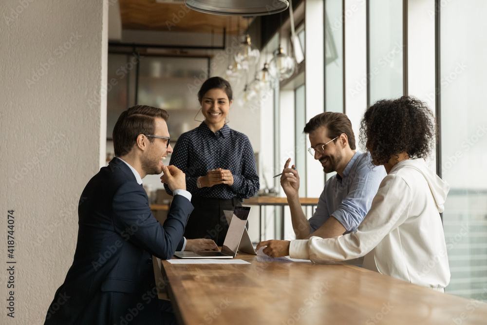 Happy diverse colleagues having fun at corporate meeting, sitting at ...