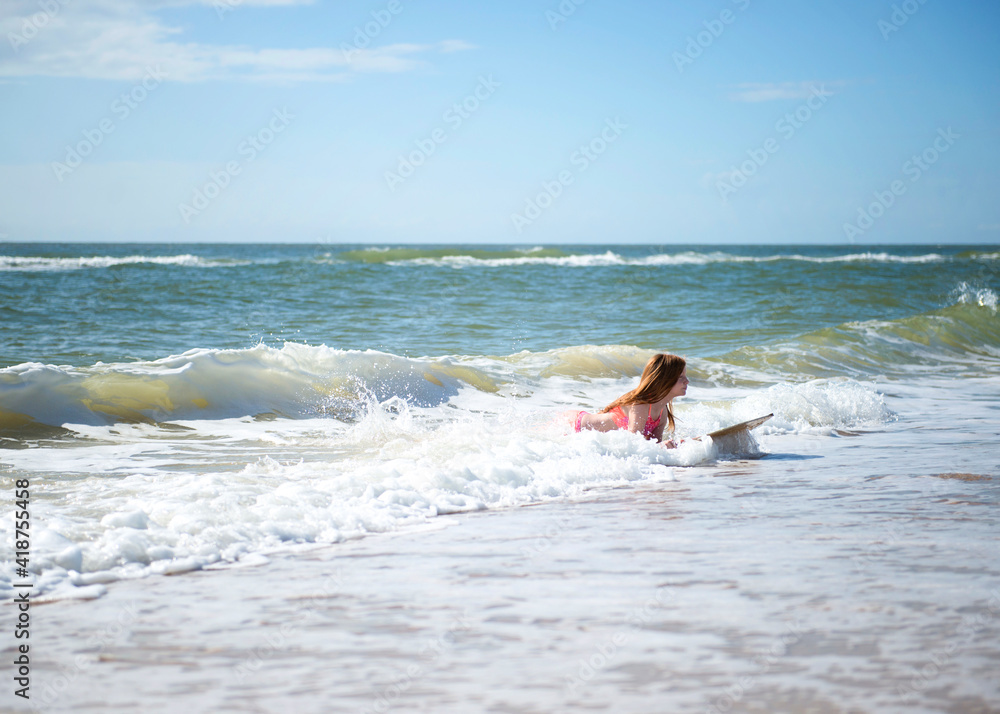 Tween red haired girl in swimsuit with boogie board at the ocean. Stock ...
