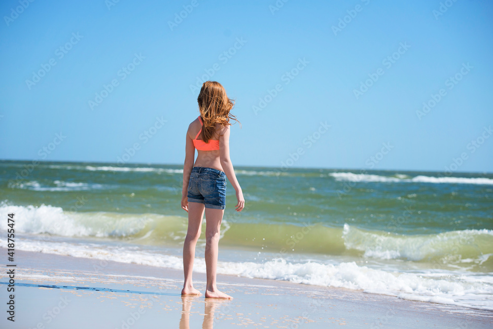 Tween red haired girl in swimsuit at the beach. Stock Photo | Adobe Stock