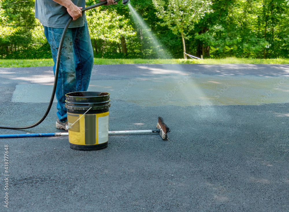 Driveway resealing repair. Spraying a light mist of water on driveway ...