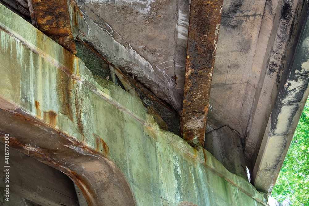 The underside of a highway bridge showing crumbling cement and rusting ...