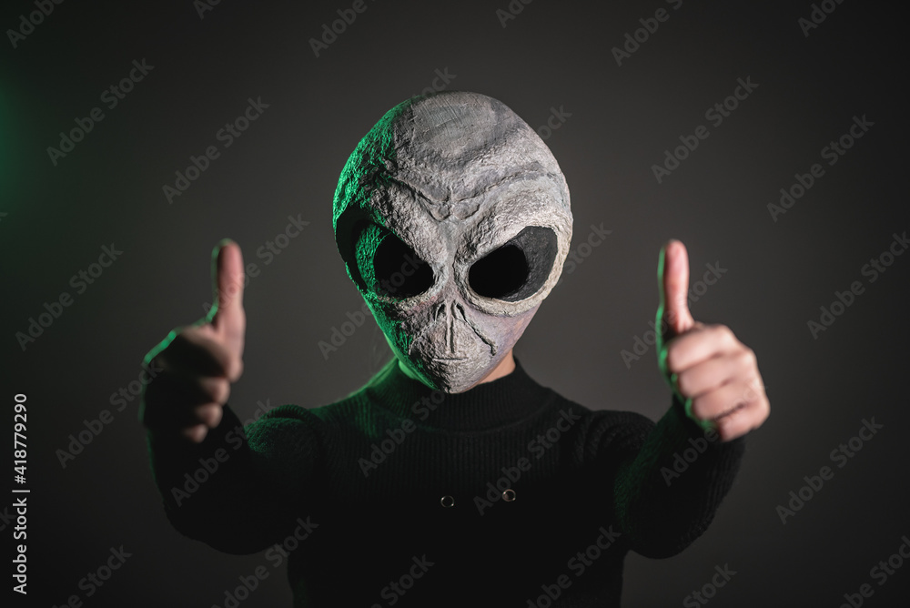 An alien is showing a thumbs up gesture on the dark background. Stock ...