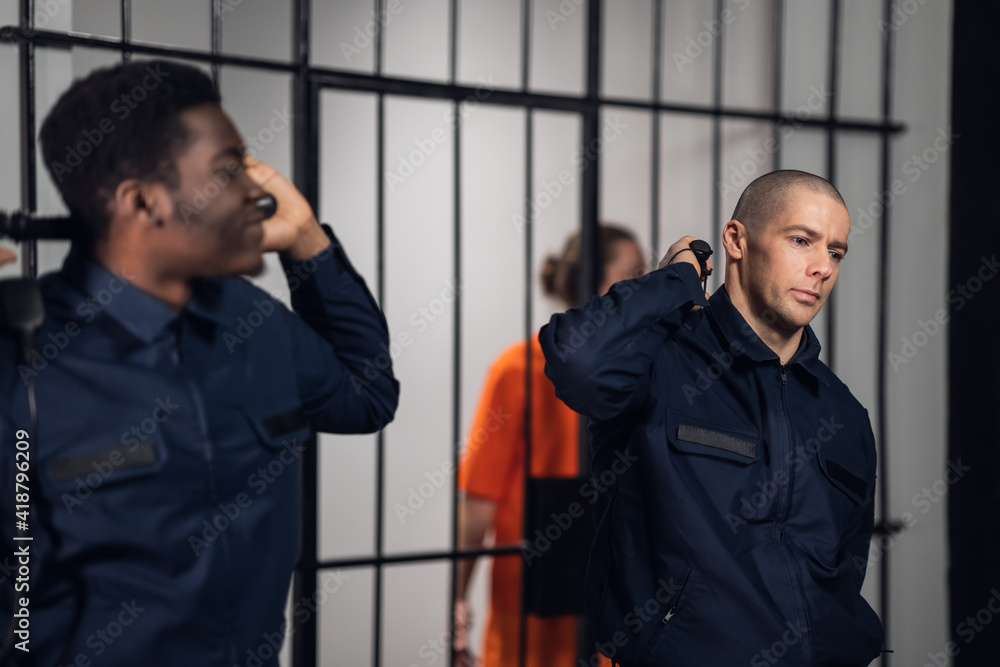 Black and white prison guards stand with batons in the background of ...