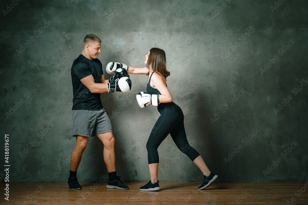 Young athletic COUPLE OF MAN AND WOMEN BOXING IN BOXING GLOVES. A WOMAN ...