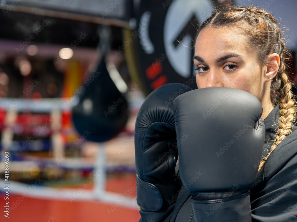 Female boxer looking at camera at the gym, working out in a boxing ring ...
