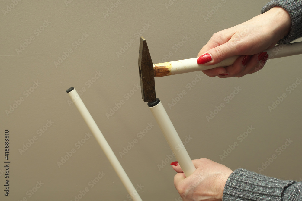 The woman collects furniture at home. Hammer with a hammer. Plastic ...