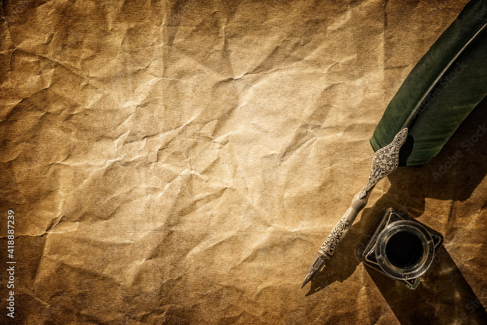 Quill pen and ink well on parchment paper background Photos | Adobe Stock