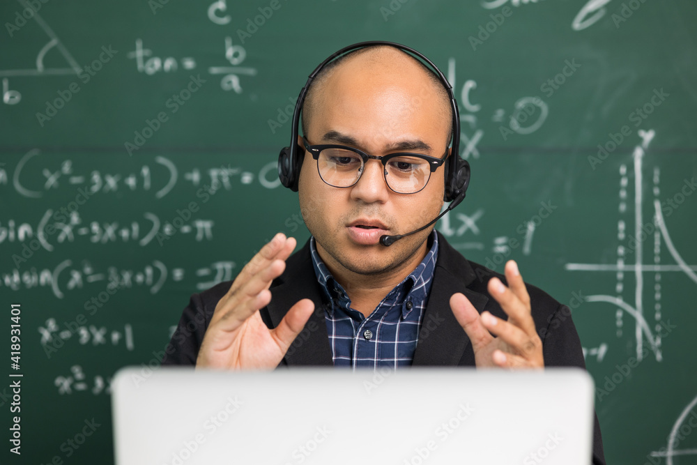 Indian young teacher man sitting wearing headset teaching online video ...