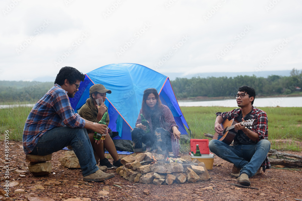Happy friends camping party playing music and enjoying bonfire in ...