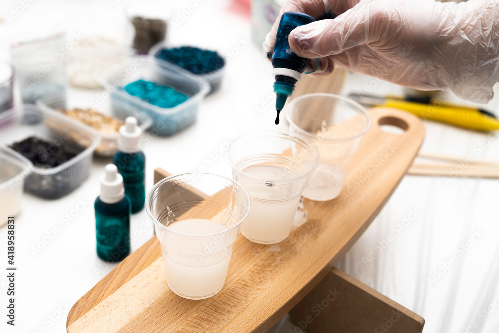 Epoxy resin DIY. A tube of blue dye in the artist's hand, against the ...