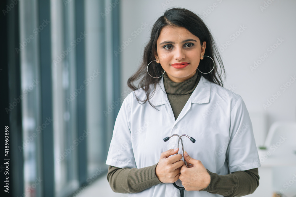 Smiling female physician posing in hospital office. Happy young indian ...