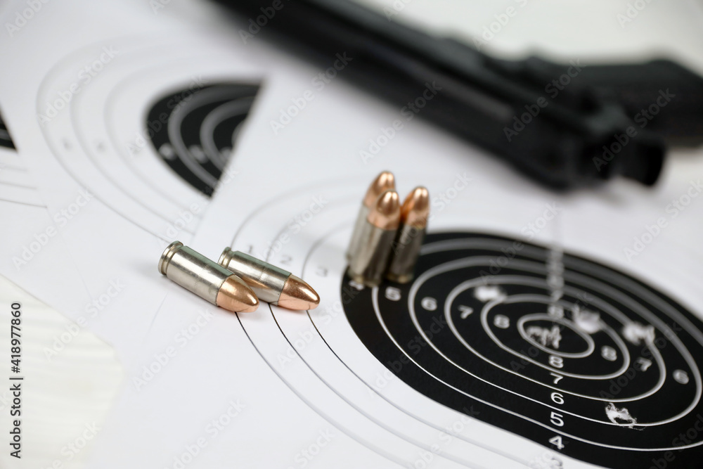 Gun and many bullets shooting targets on white table in shooting range ...