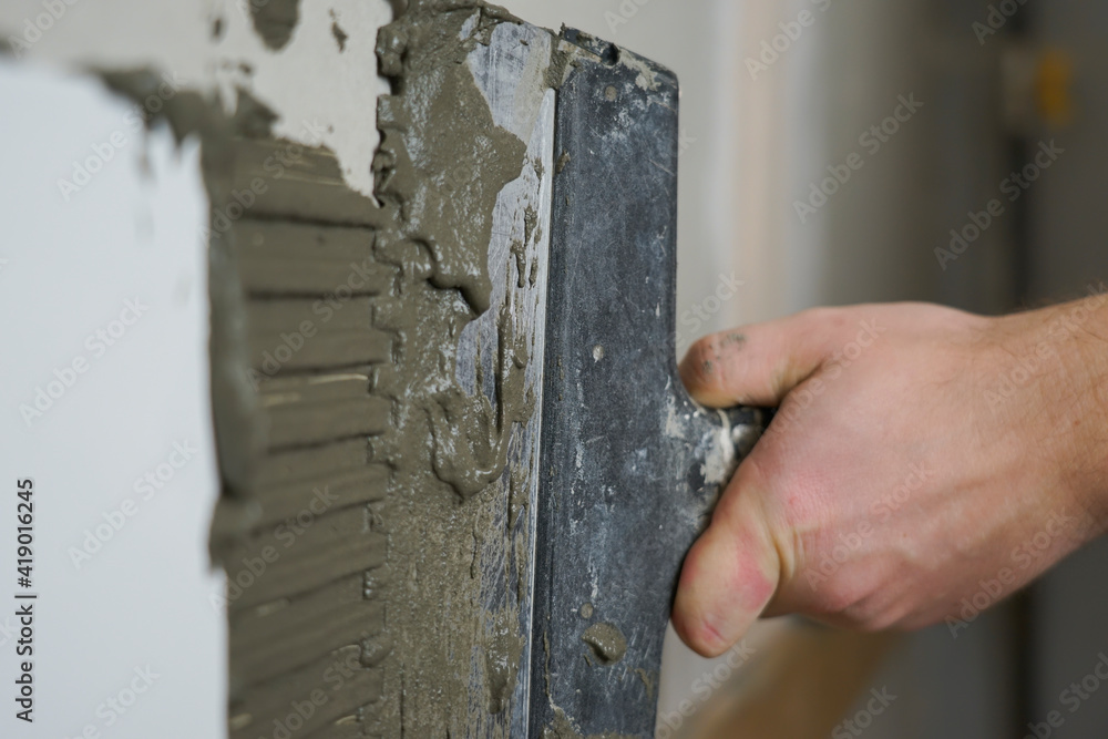 Comb trowel with cement mortar for gluing tiles. Tiling and home ...