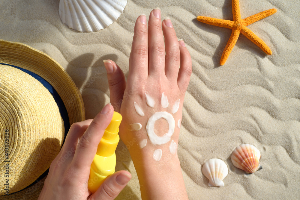 Hands with sunscreen. Seashells, starfish, sun hat, sunscreen and hand ...