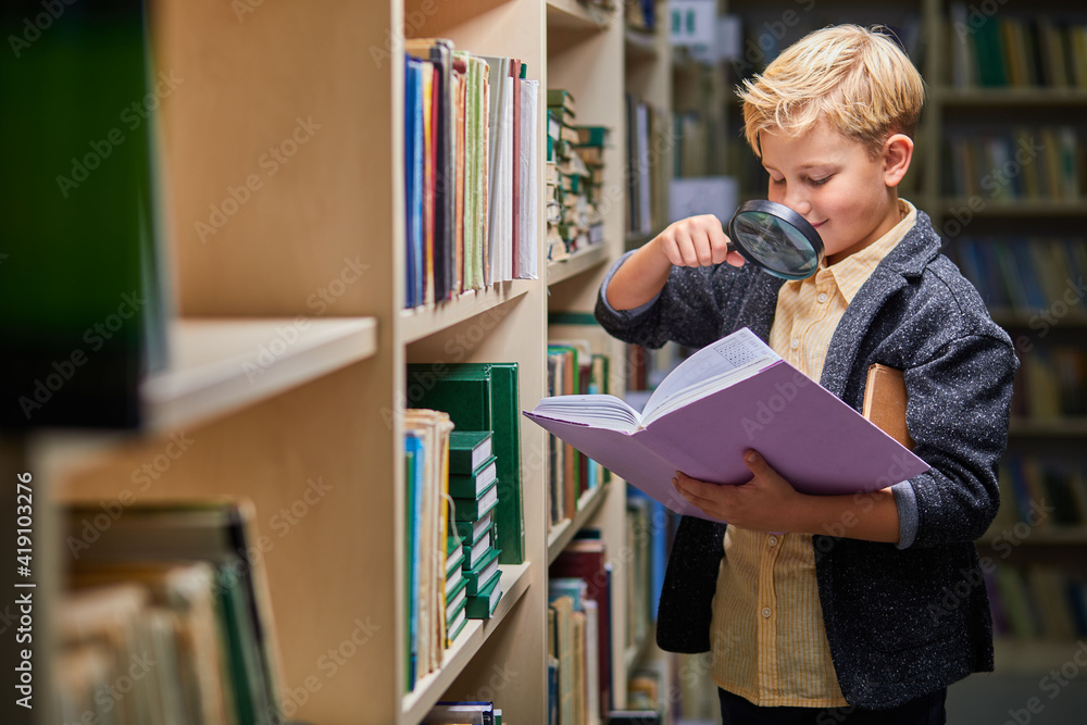 Fotografia do Stock: preschool boy reading book in library with ...