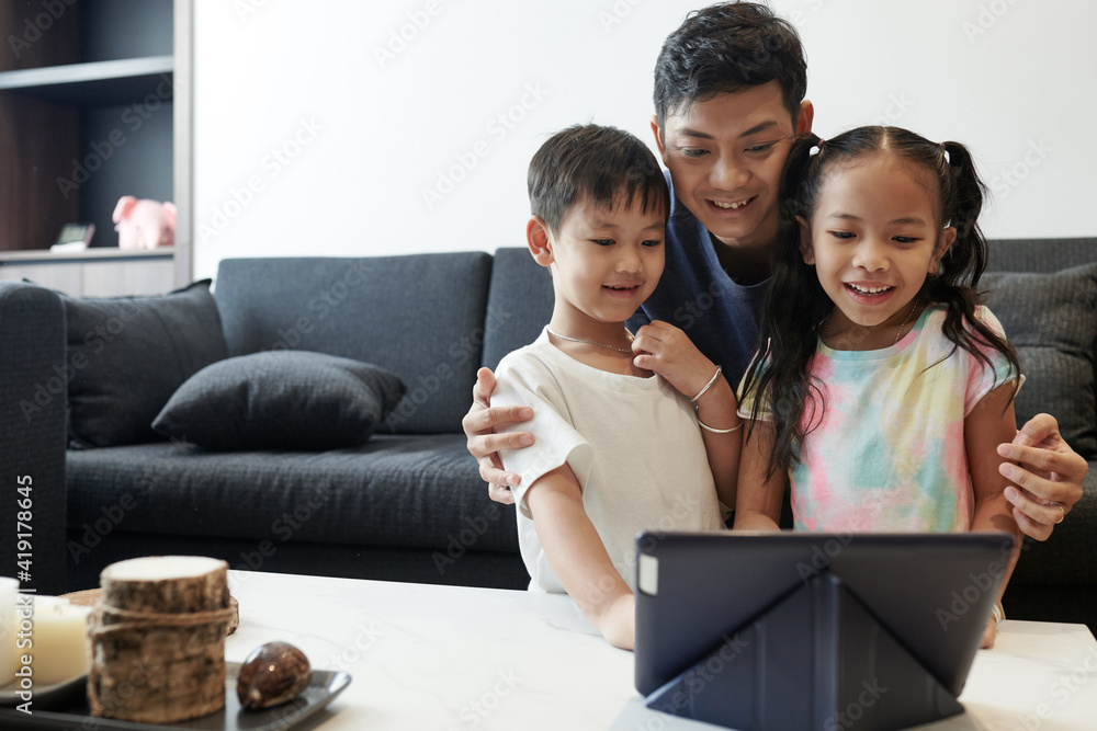 Excited father and his two kids watching new animated show on tablet ...