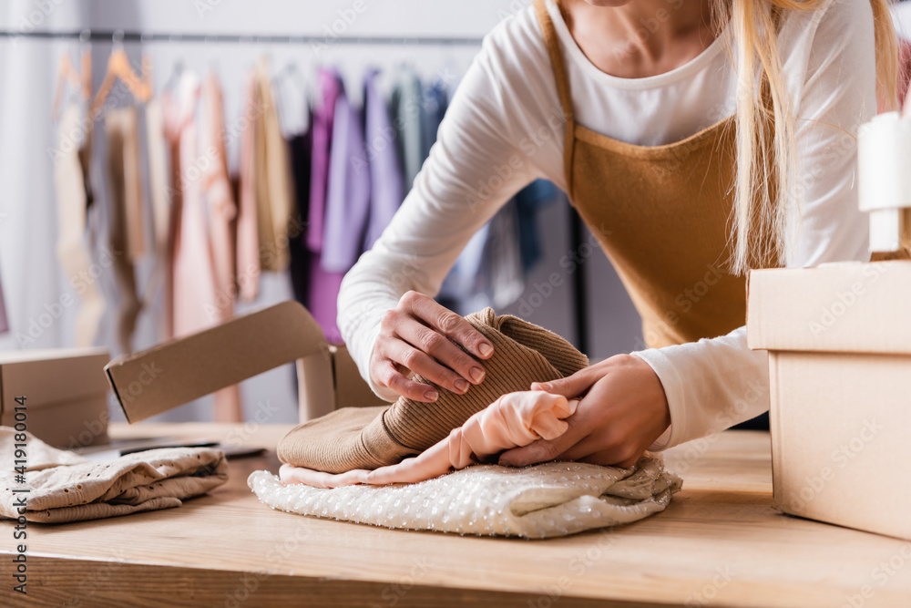 cropped view of showroom owner counting clothes near cardboard boxes ...