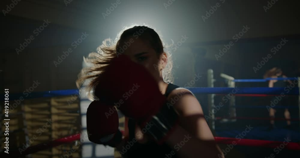 Portrait of strong athletic young woman throwing punches facing camera ...