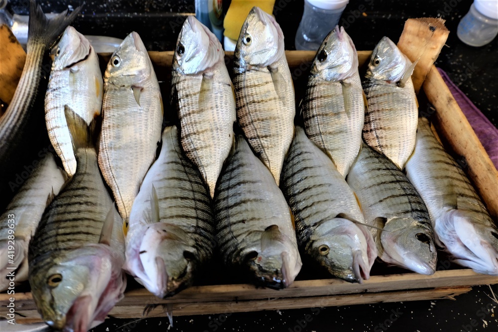 Foto de Fresh fishes in wooden box on kitchen table, selective focus ...