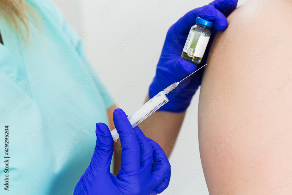 Close up of a Doctor making a vaccination in the shoulder of patient ...