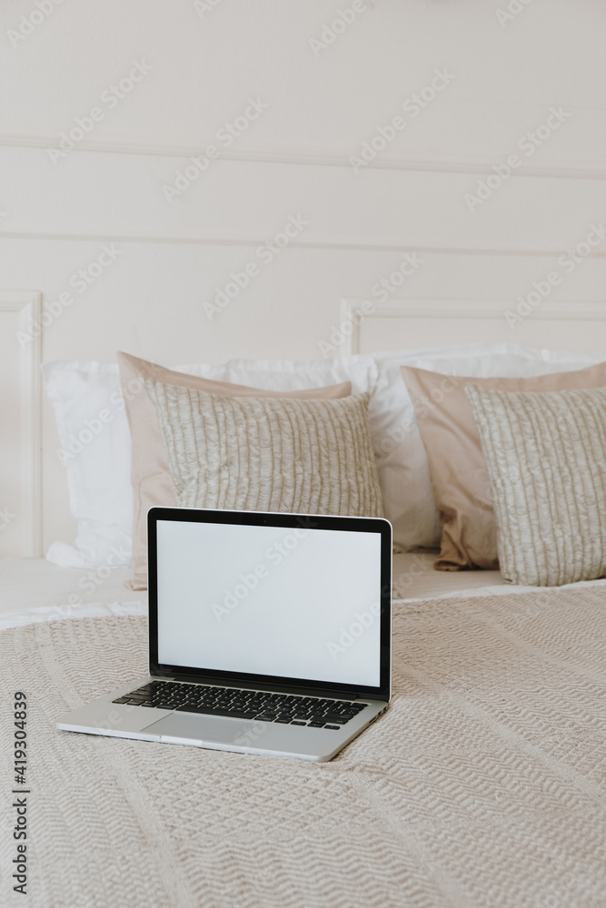 Blank screen laptop in bed with pillows and linens. Classic style bed ...