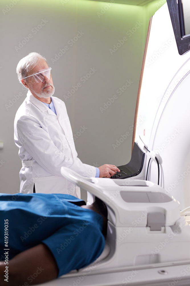 Male Patient Lying On MRI Machine While Elderly professional Doctor ...