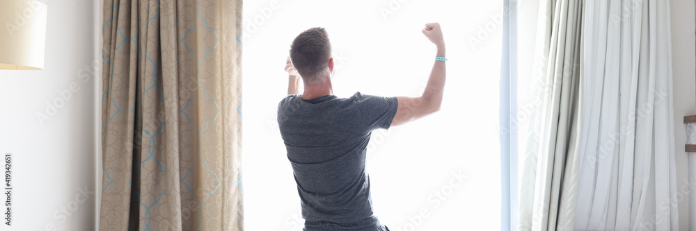 Man stands with his back against window and holds his hands up ...