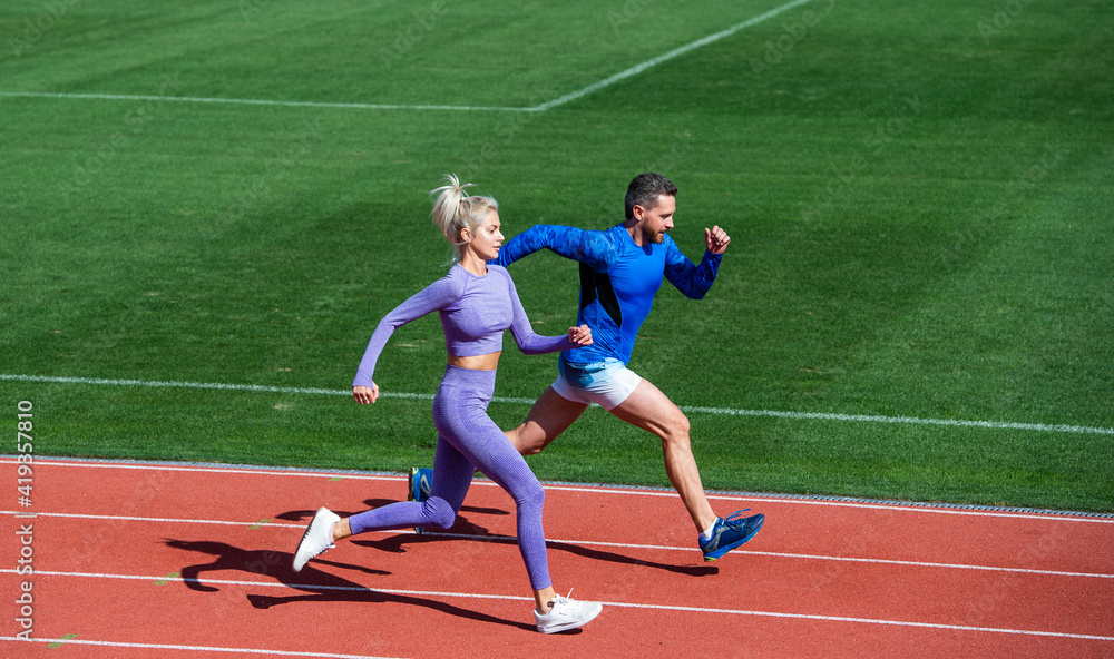 athletic man and woman of sprinters run on running track at stadium ...