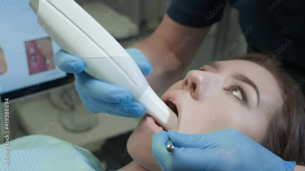 Doctor scans the patient's teeth in the clinic. The dentist holds in ...