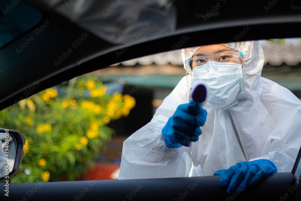 Medical staff with PPE use infrared thermometer gun to check body ...