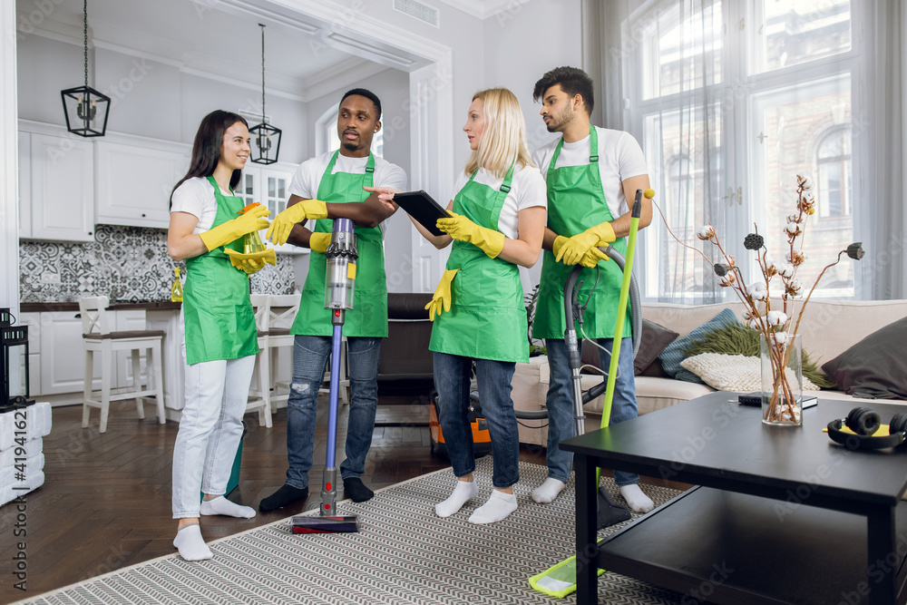 Multiracial team of cleaning service using digital tablet and talking ...