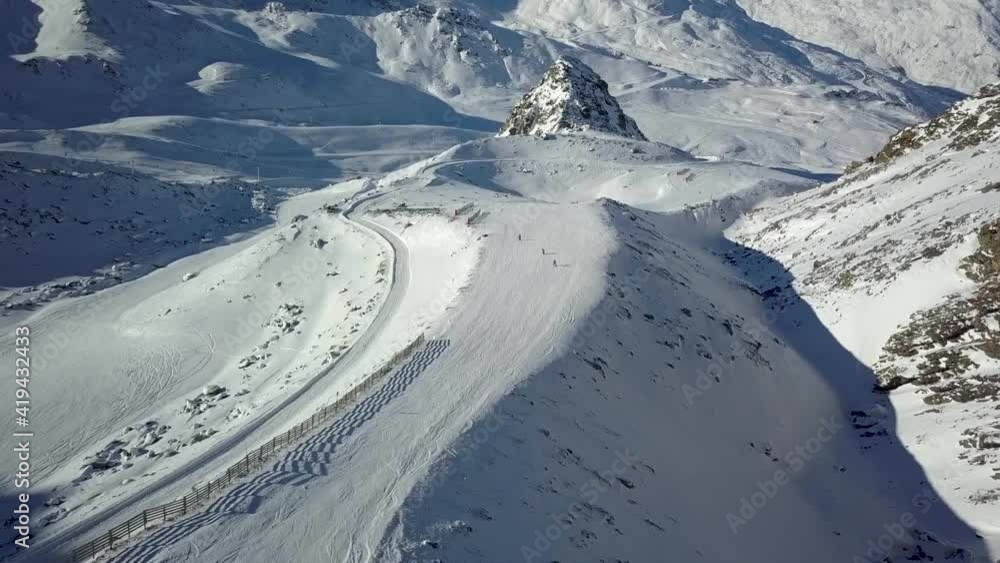 Downhill ski track amidst frozen barren landscape of Val Thorens ...