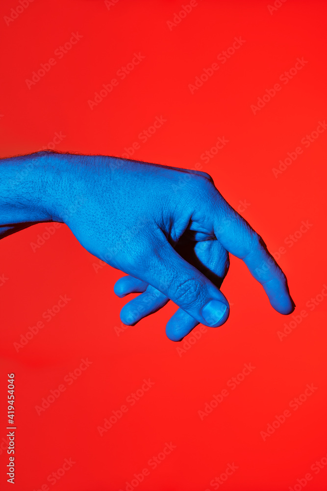 Man's blue finger pointing downwards over red background. Isolated ...