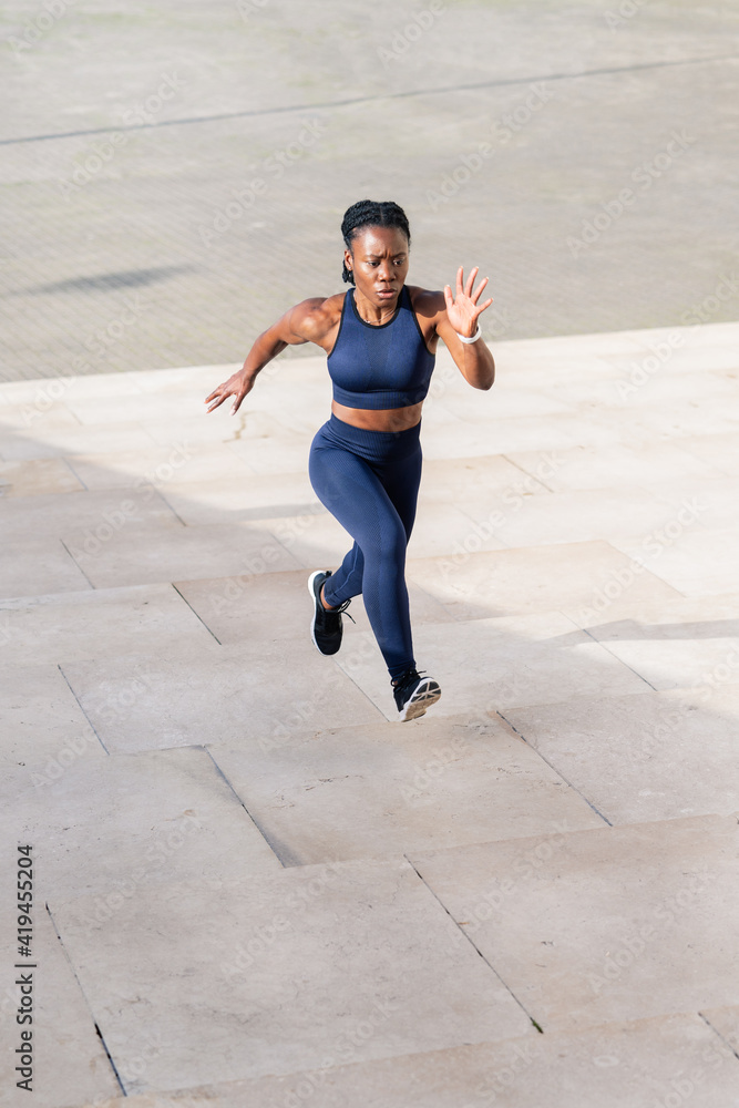 black afro girl dressed as a runner running up a flight of steps in the ...