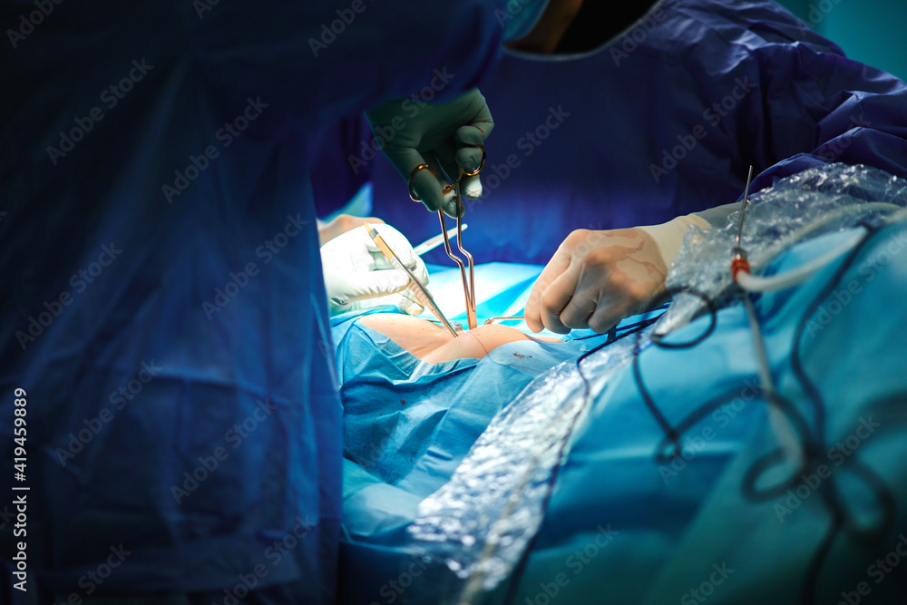 Crop anonymous surgeon with assistant in sterile gowns and gloves using ...