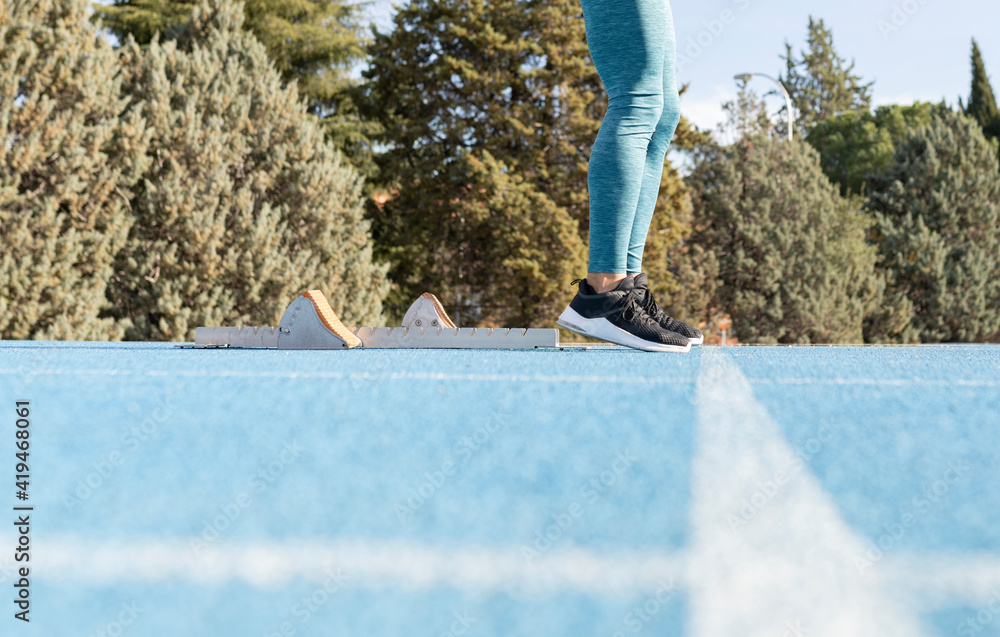 Ground level side view of runner standing on track near starting blocks ...