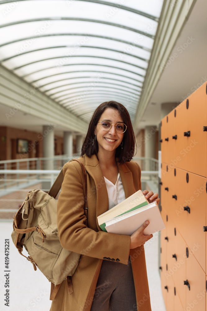 Smiling female student in smart casual outfit standing in university ...