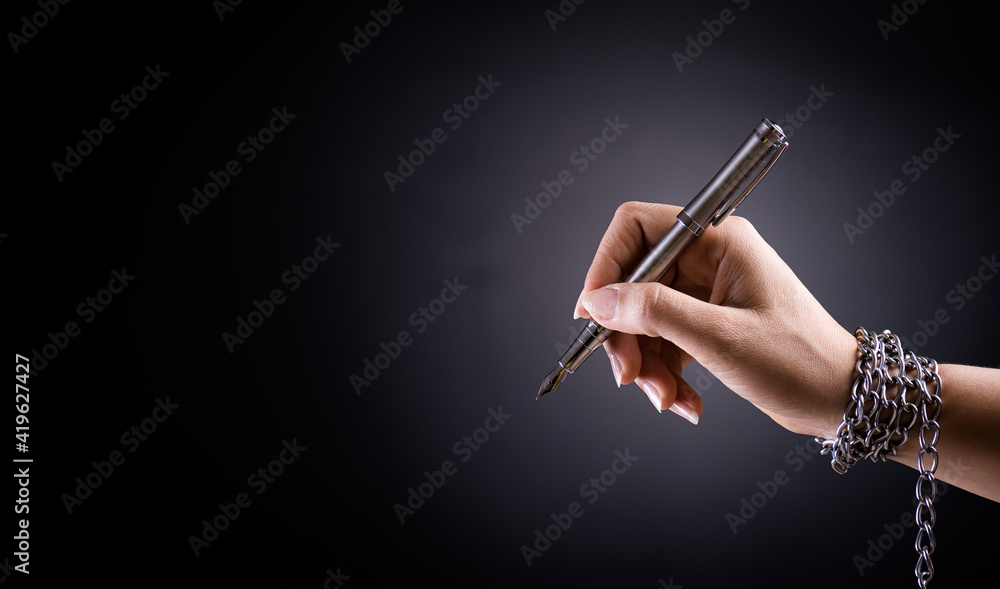 World press freedom day concept. Hand holding a pen with chain on dark ...