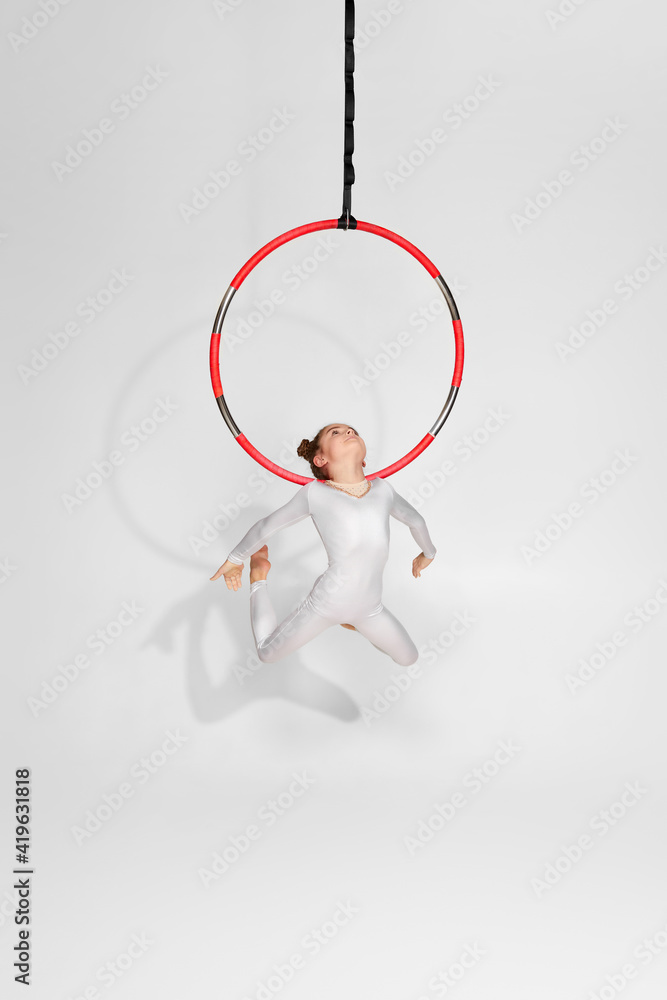 graceful child girl gymnast in white sportwear shows an acrobatic ...