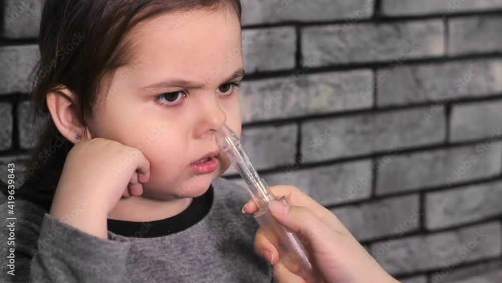 Mother clean her daughter nose using baby nasal aspirator. Mucus and ...
