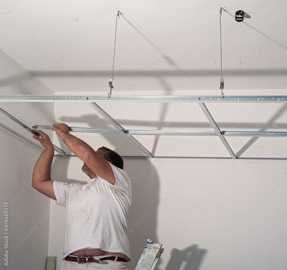 Construction worker assemble a suspended ceiling with drywall an. D ...