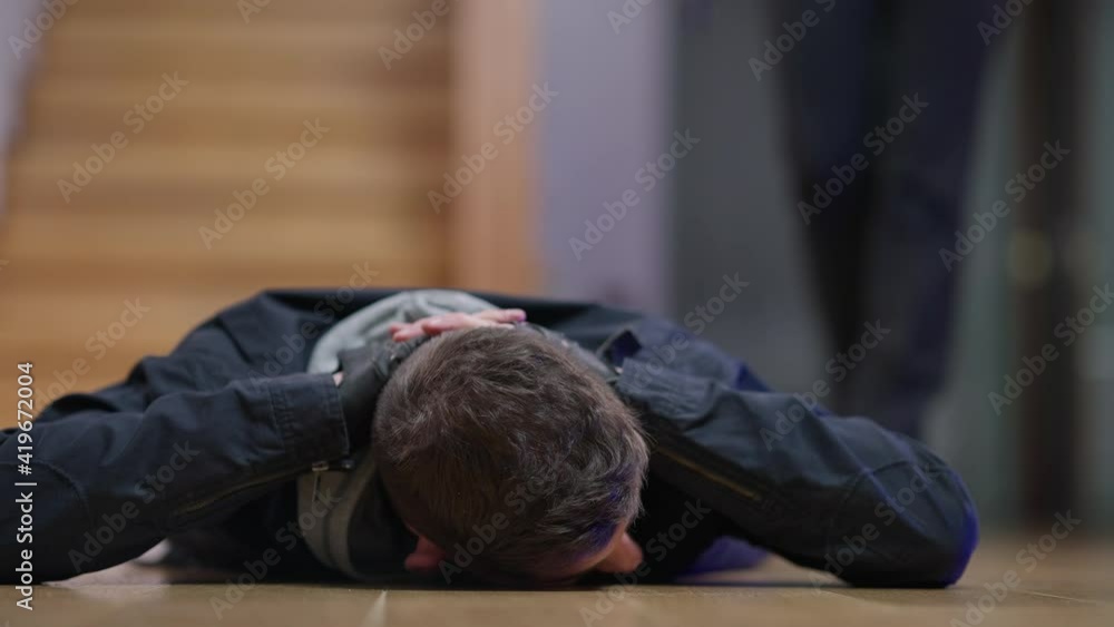 Arrested young criminal lying on floor in police lights holding hands ...