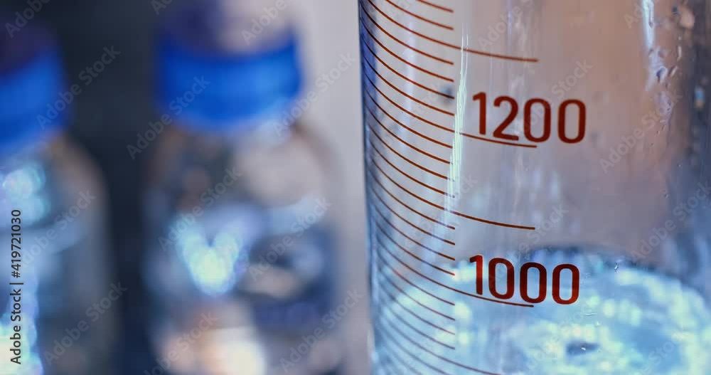 A transparent liquid illuminated with blue light is poured into a ...