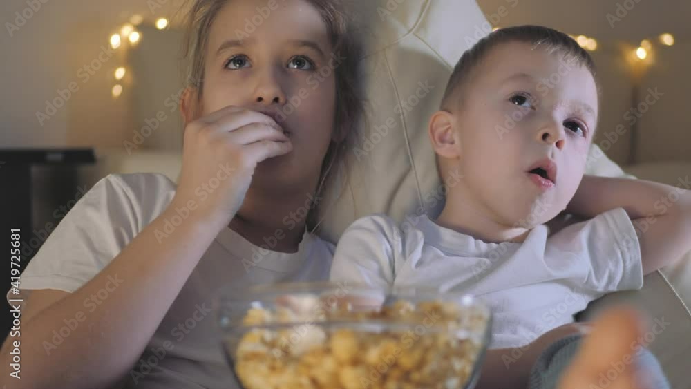 Happy family, brother and sister watching tv with popcorn bowl at home ...