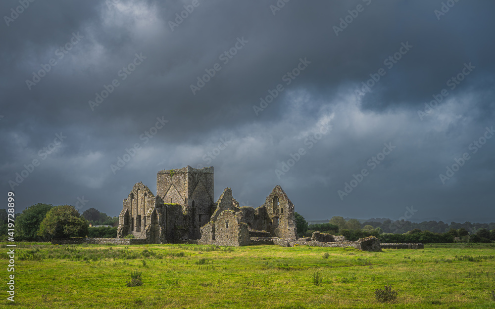 Old ruins of Hore Abbey illuminated by sunlight with dark dramatic ...