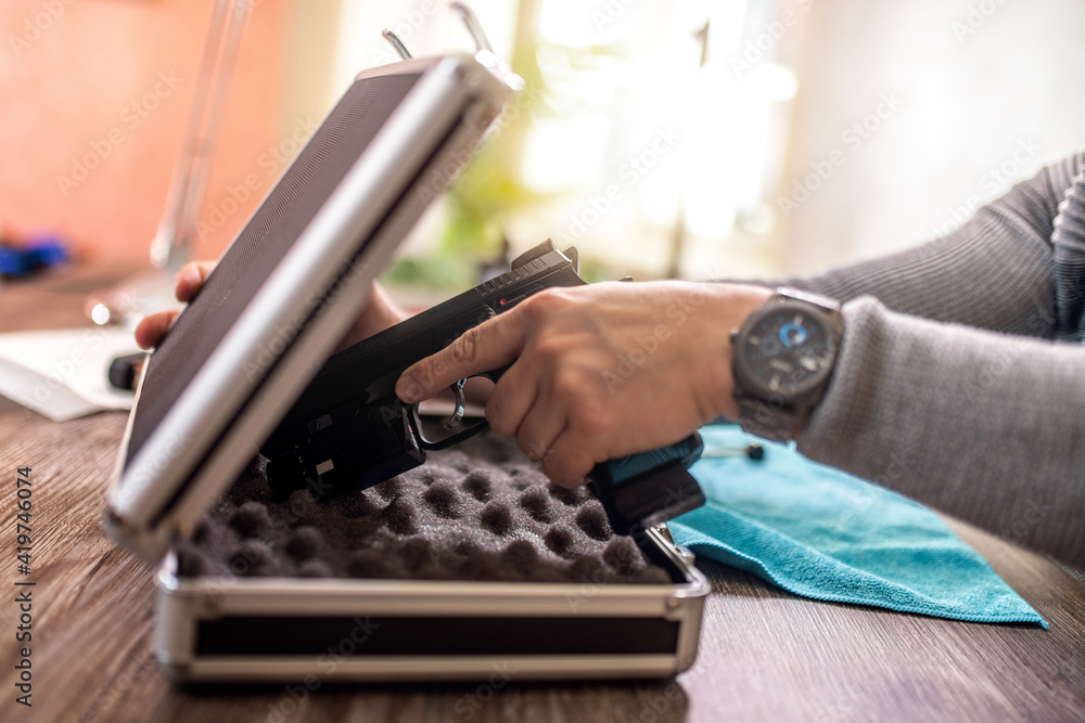 Man putting gun in safe box Stock Photo | Adobe Stock