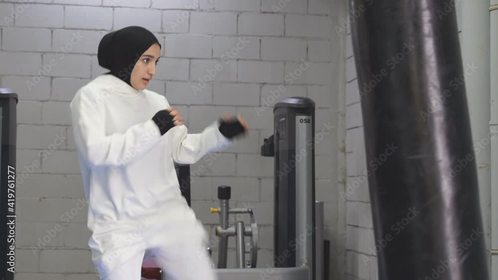 Muslim athlete, a woman wearing a sports hijab, preparing to strike, a ...