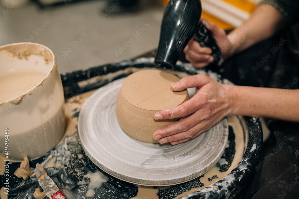 Woman sculptor creating ceramics using wheel in a pottery using potter ...