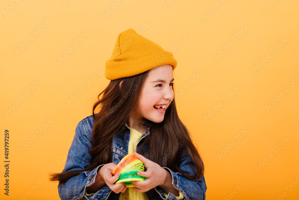 Beautiful young girl playing with a rainbow slinky, a toy of her ...