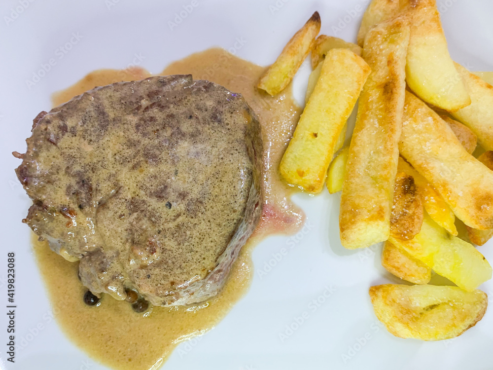 Filetto di maiale cotto al sangue con contorno di patate fritte Stock ...